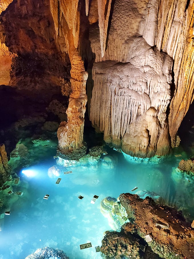 Turquoise waters shimmer beneath ancient stalactites, with dollar bills scattered like modern offerings to underground spirits. Cave pools and human superstition—a timeless combination.