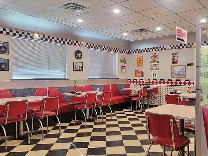 Red booths invite you to slide in and stay awhile. The checkered pattern isn't just on the floor—it's the rhythm of diner life itself.