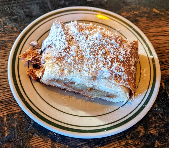 Apple strudel dusted with powdered sugar—the kind of dessert that makes you push through fullness because missing it would be a culinary crime.