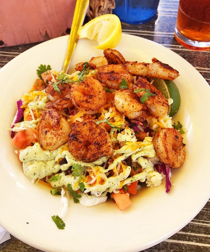 "Blackened shrimp perched atop a colorful salad – proof that 'eating healthy' and 'absolutely delicious' aren't mutually exclusive concepts."