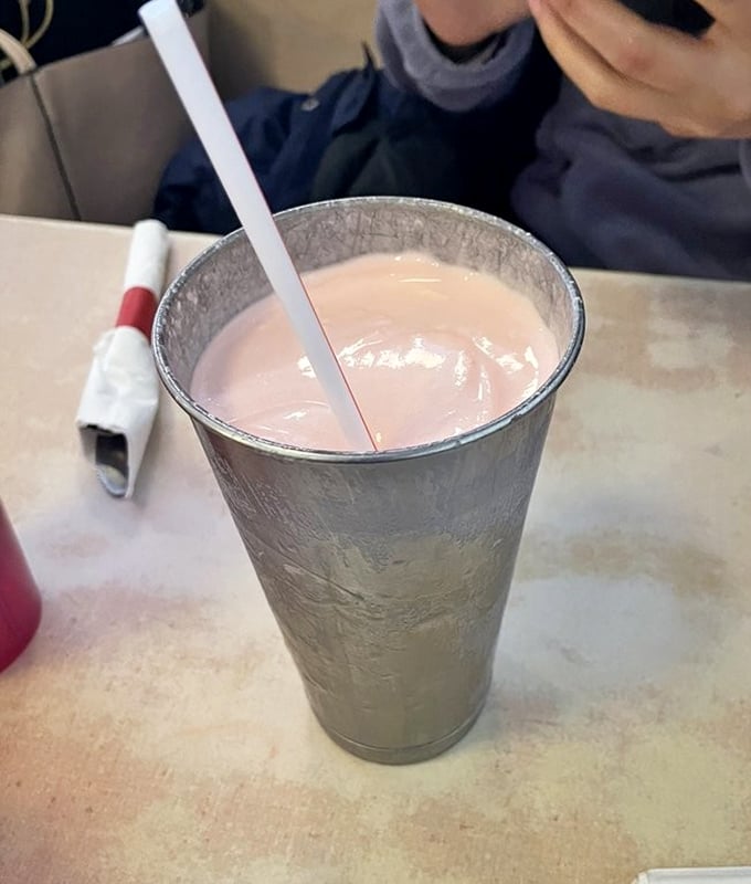 A milkshake so thick the straw stands at attention—part dessert, part beverage, all indulgence in a frosty metal cup.