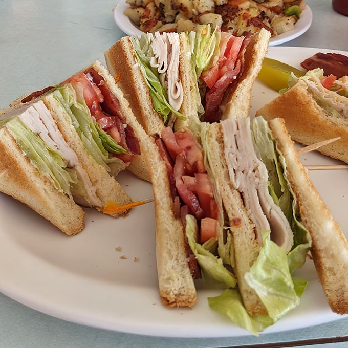 The club sandwich—a towering achievement of turkey, bacon, and vegetables that requires both hands and a strategic approach.