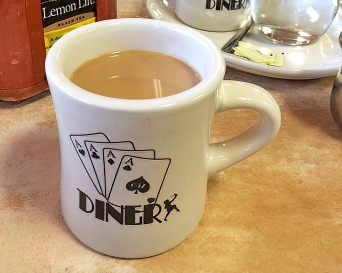 The Four Aces coffee mug—holding the elixir that transforms morning zombies into functioning humans one sip at a time.