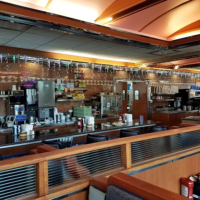 The counter and kitchen—diner theater at its finest, where coffee mugs are never empty and the griddle sizzles with constant promises.