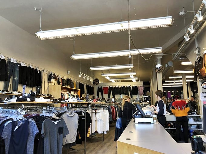 Behind the sleek wooden counter, fashion gatekeepers evaluate potential inventory while shoppers browse—the circular economy spinning in real time.