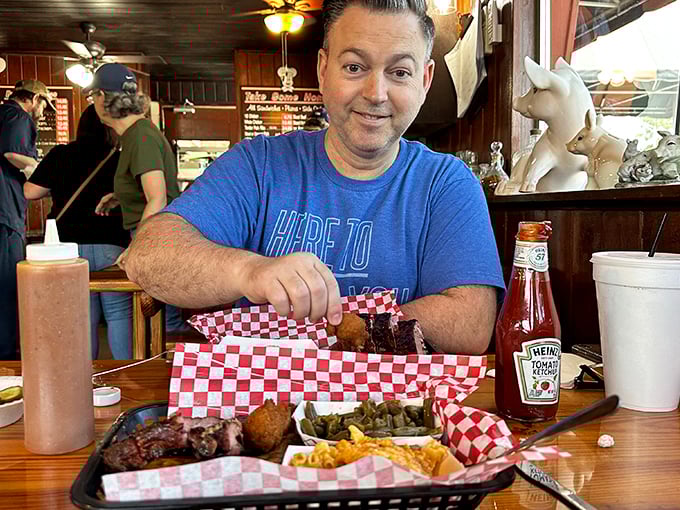 In the image, a diner prepares to tackle a barbecue feast spread before him—the red-checkered paper suggests this isn't his first rodeo.