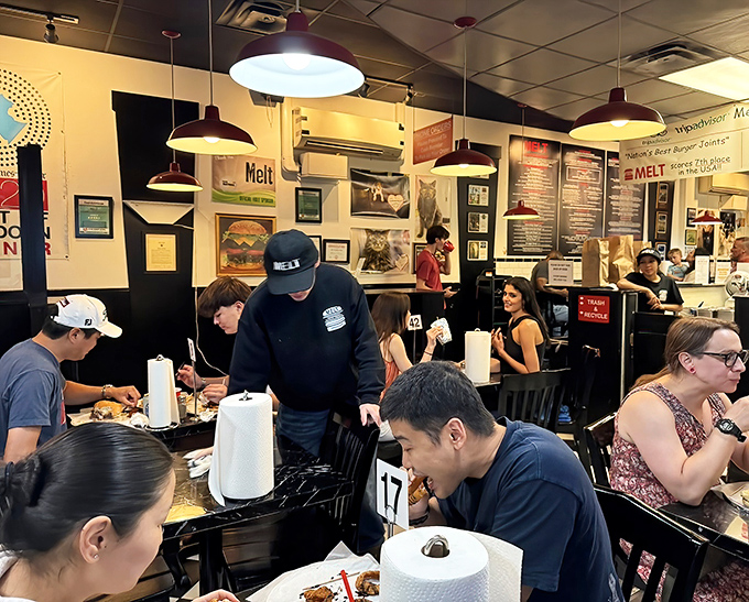 A packed house of burger enthusiasts engaged in the sacred ritual of the perfect bite. Notice the absence of phones – food this good demands full attention.
