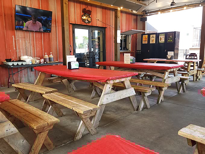 Red picnic tables under string lights – barbecue's natural habitat where paper towels are currency and sauce stains are badges of honor.