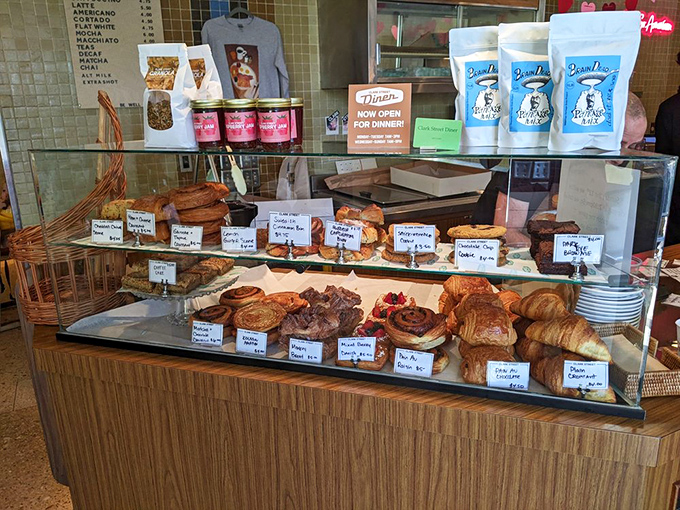 The pastry case—a glass-enclosed museum of carbohydrate artistry where willpower goes to die a delicious death.