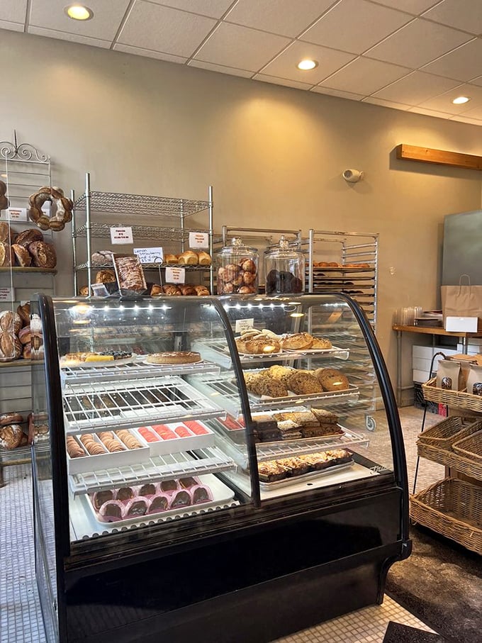 The curved glass case – a museum of carbohydrate masterpieces where willpower goes to surrender gracefully.