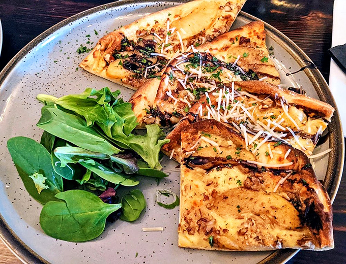 This flatbread isn't just a pizza's sophisticated cousin – it's a crispy canvas where caramelized toppings and melted cheese create edible art.