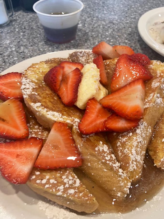 French toast that's had a spa day – thick-cut bread soaked in custard, grilled to perfection, then adorned with fresh strawberries and a dusting of powdered sugar.