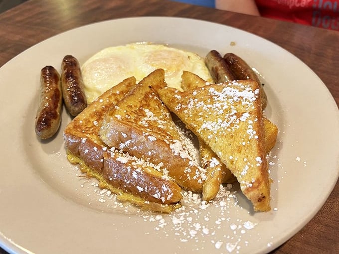 French toast dusted with powdered sugar, eggs cooked just right, and sausage links that snap when you bite them—breakfast perfection on a plate.