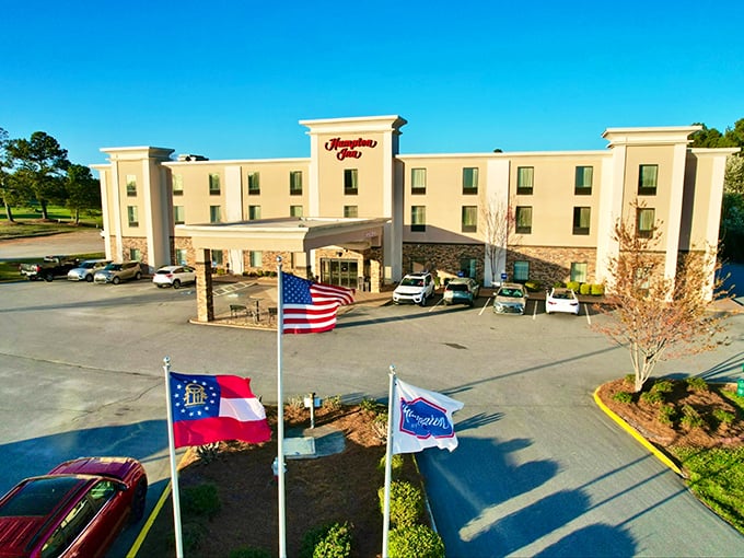 The Hampton Inn flies Georgia's flag alongside Old Glory, welcoming visitors with that chain-hotel reliability wrapped in small-town Southern hospitality.