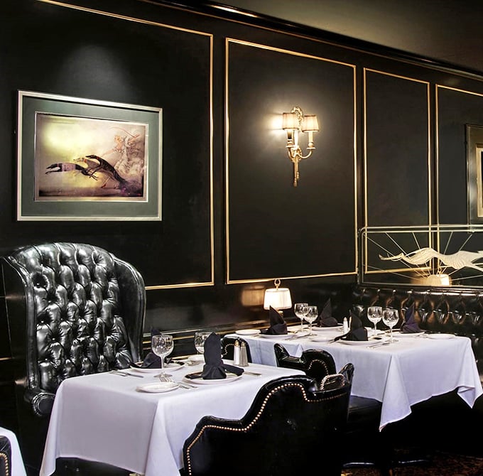 Tufted leather booths create intimate kingdoms for conversation. These black leather thrones, paired with crisp linens and gold accents, make every diner feel like visiting royalty.