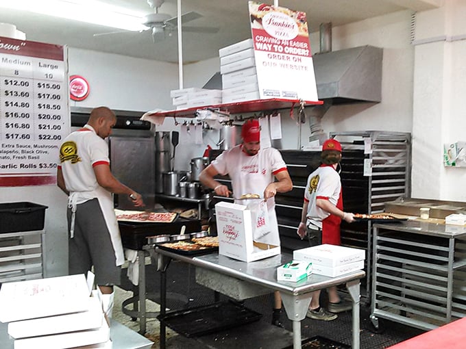 Behind the scenes, the pizza-making ballet continues as it has for decades – practiced hands creating edible masterpieces with methodical precision.