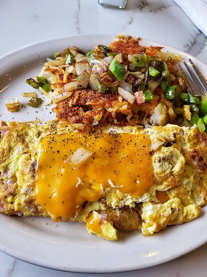 This omelet has achieved the impossible – perfectly cooked eggs embracing melted cheese alongside potatoes that are basically hash brown royalty.
