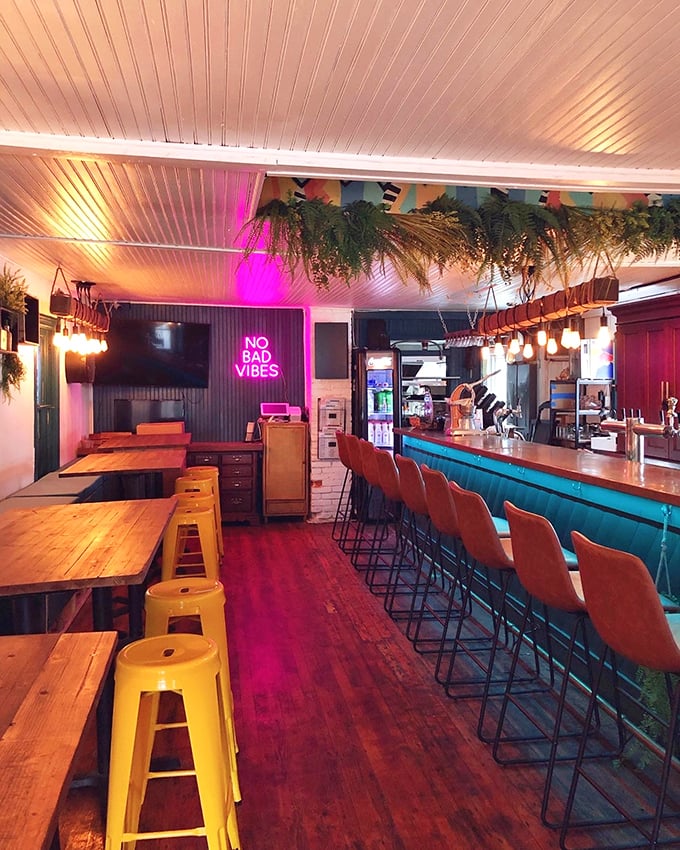 Inside, the "No Bad Vibes" neon isn't just decoration—it's a promise kept through ambient lighting and lush hanging plants that soften the industrial elements.