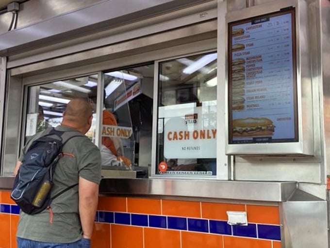 The ordering window—where dreams come true and tourists learn the local lingo. "Wit or witout" is the password to sandwich paradise.