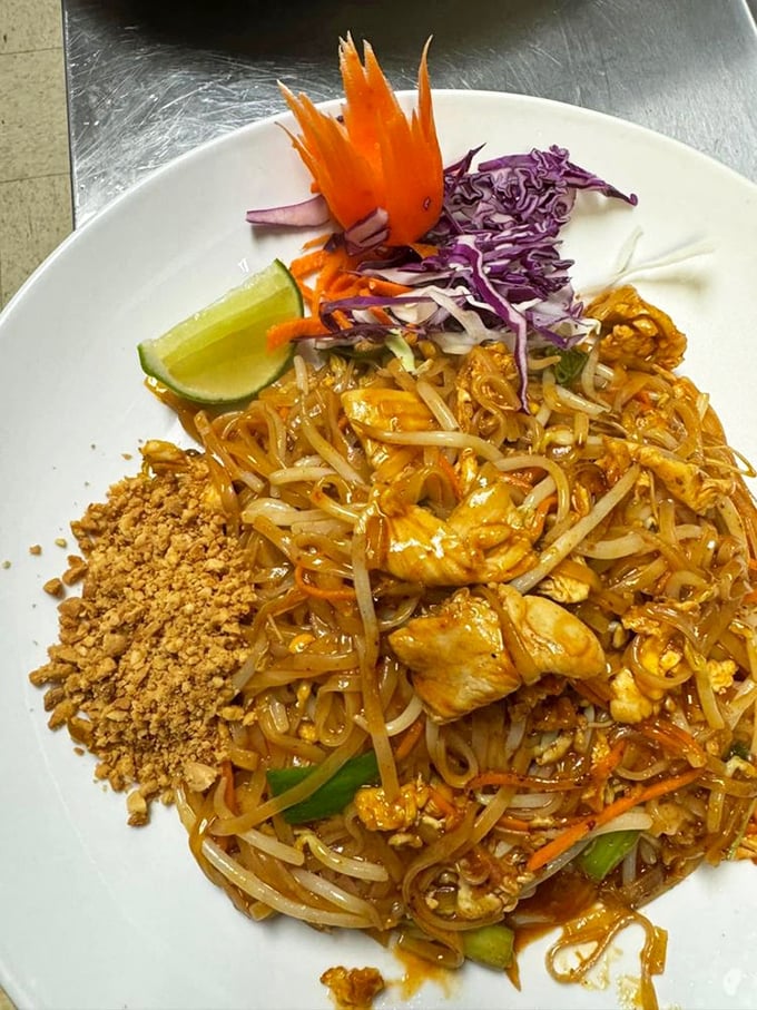 Pad Thai presented with architectural precision—crushed peanuts waiting to join the party, purple cabbage adding pop, and a lime wedge standing by for duty.