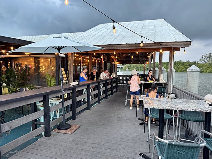 As evening approaches, the string lights twinkle to life, transforming an already magical waterfront spot into pure dining enchantment.