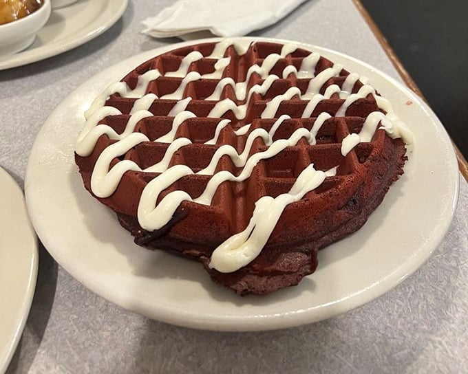 Red velvet waffle with cream cheese drizzle - breakfast that thinks it's dessert, and nobody's complaining about the confusion.