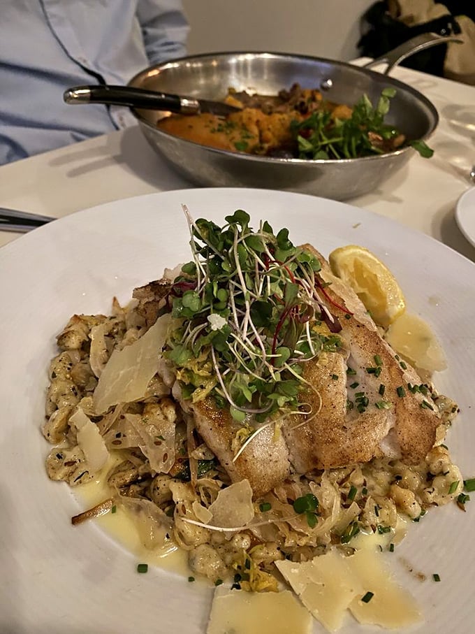 The roasted fish sits atop a bed of vegetables, microgreens adding both color and a peppery punch to this perfectly executed plate.