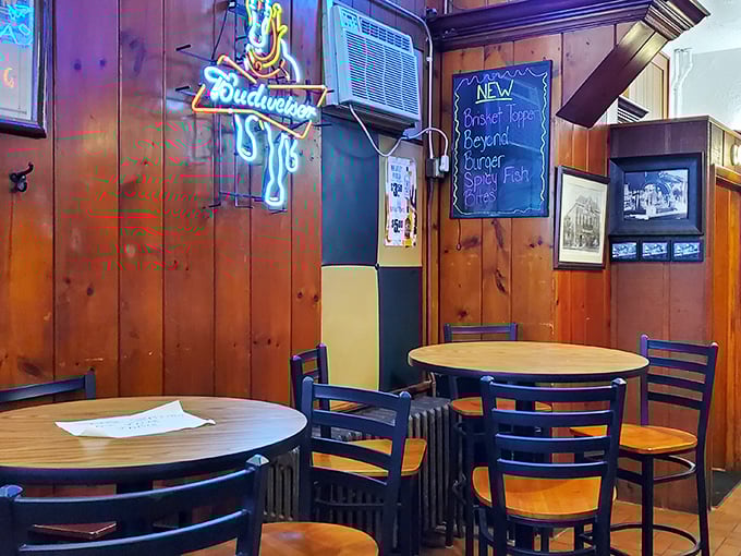 Neon signs cast their colorful glow over simple round tables, creating the perfect backdrop for both quiet conversations and boisterous celebrations.