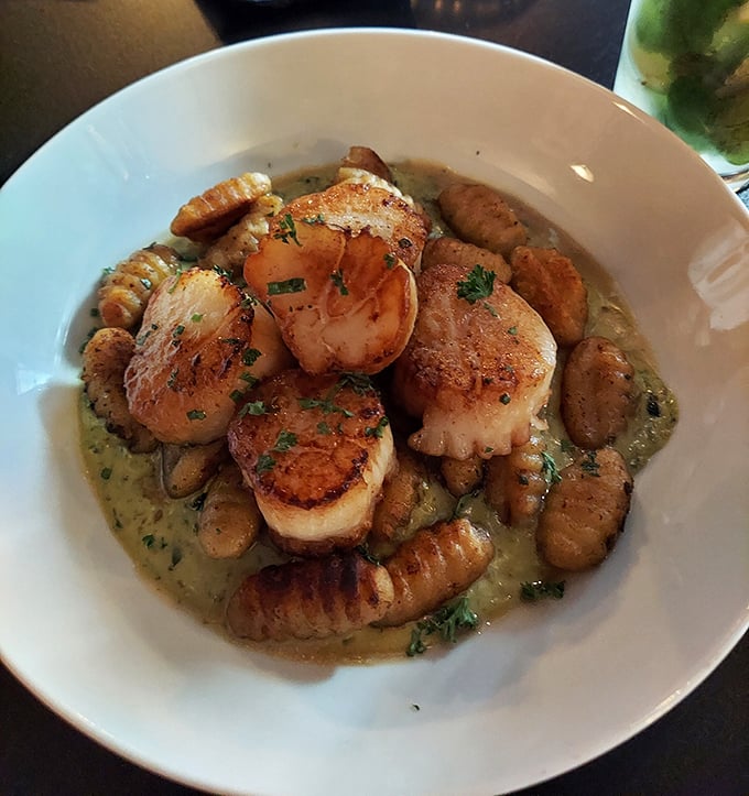 Perfectly seared scallops lounging in a savory broth with gnocchi—like pillowy life rafts in a sea of flavor.