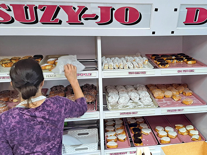 Careful hands arranging tomorrow's happiness. Each tray represents not just donuts, but moments of joy waiting to be discovered.