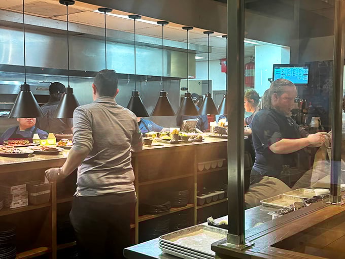 Behind the glass, barbecue artisans orchestrate a symphony of smoke and fire—the kitchen view is dinner and a show.