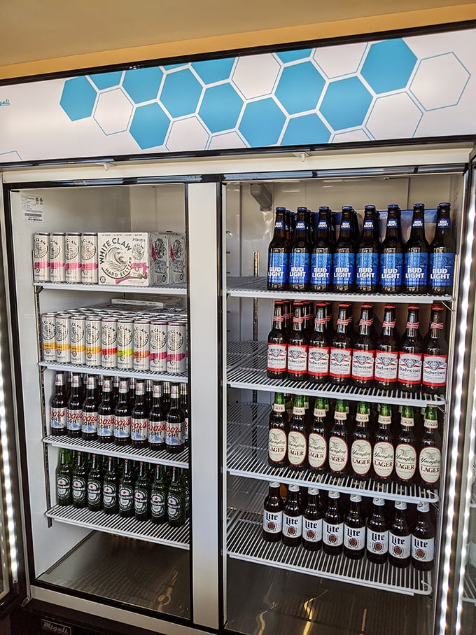 The beer cooler—where domestic brews and craft seltzers live together in peaceful, chilled harmony, waiting for their barbecue soulmate.