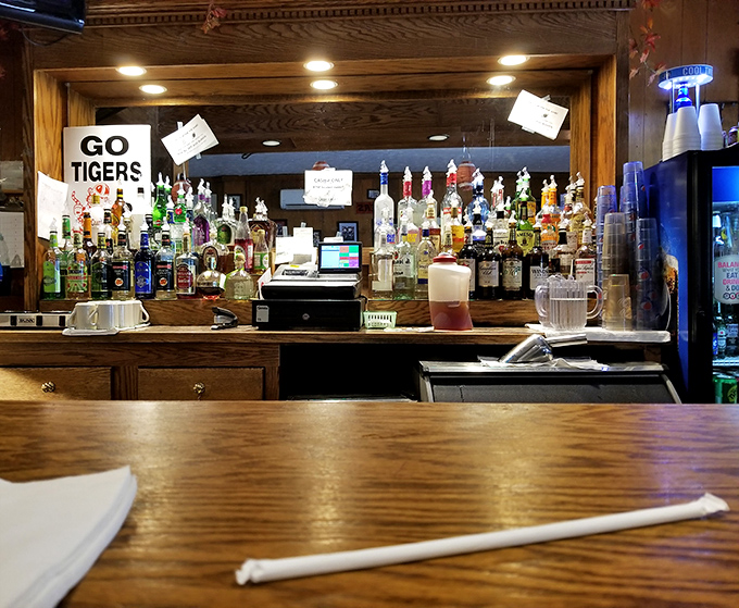 The bar area—where "Go Tigers" signs and liquor bottles create the perfect backdrop for solving world problems.