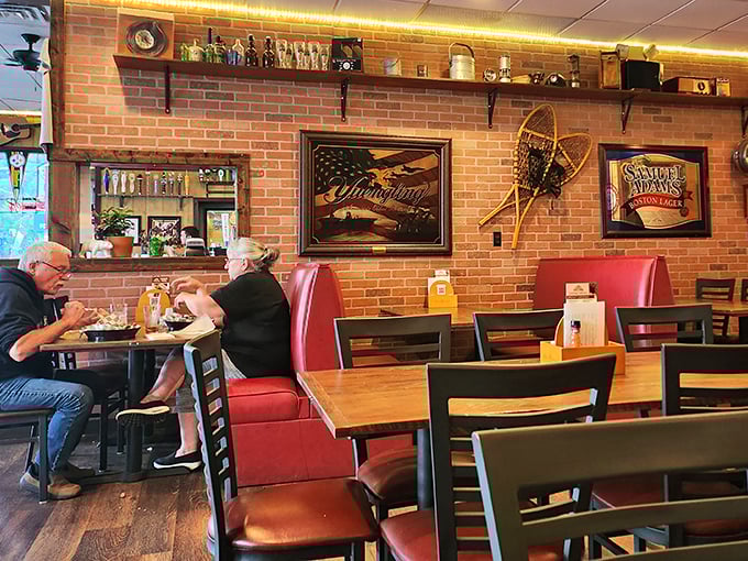 Red booth seating against exposed brick walls—the classic American pub experience where comfort meets craftsmanship in both food and atmosphere.