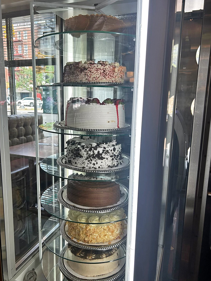 The rotating dessert display—a glass tower of temptation that makes willpower crumble faster than their apple pie crust.