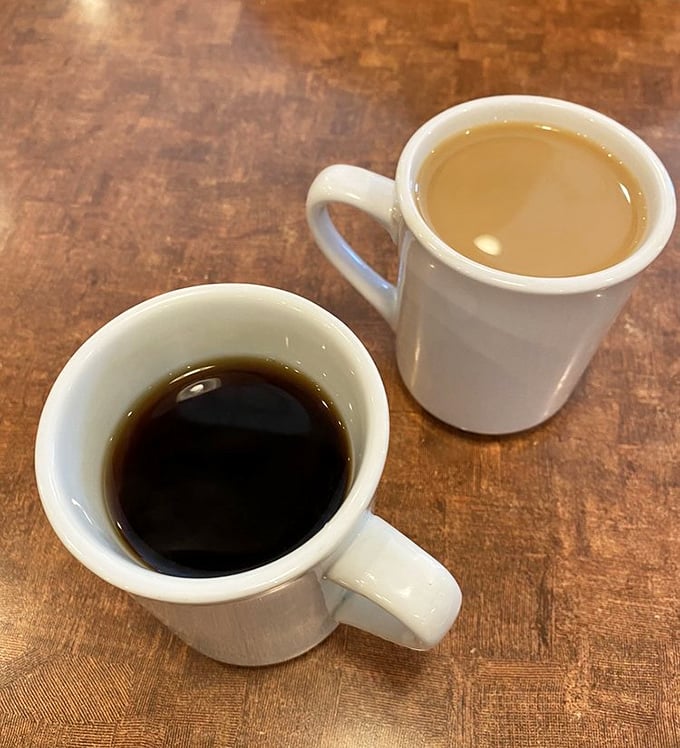 Coffee served two ways: black as midnight or lightened with cream – either way, it's the lifeblood that powers Nick's morning regulars.