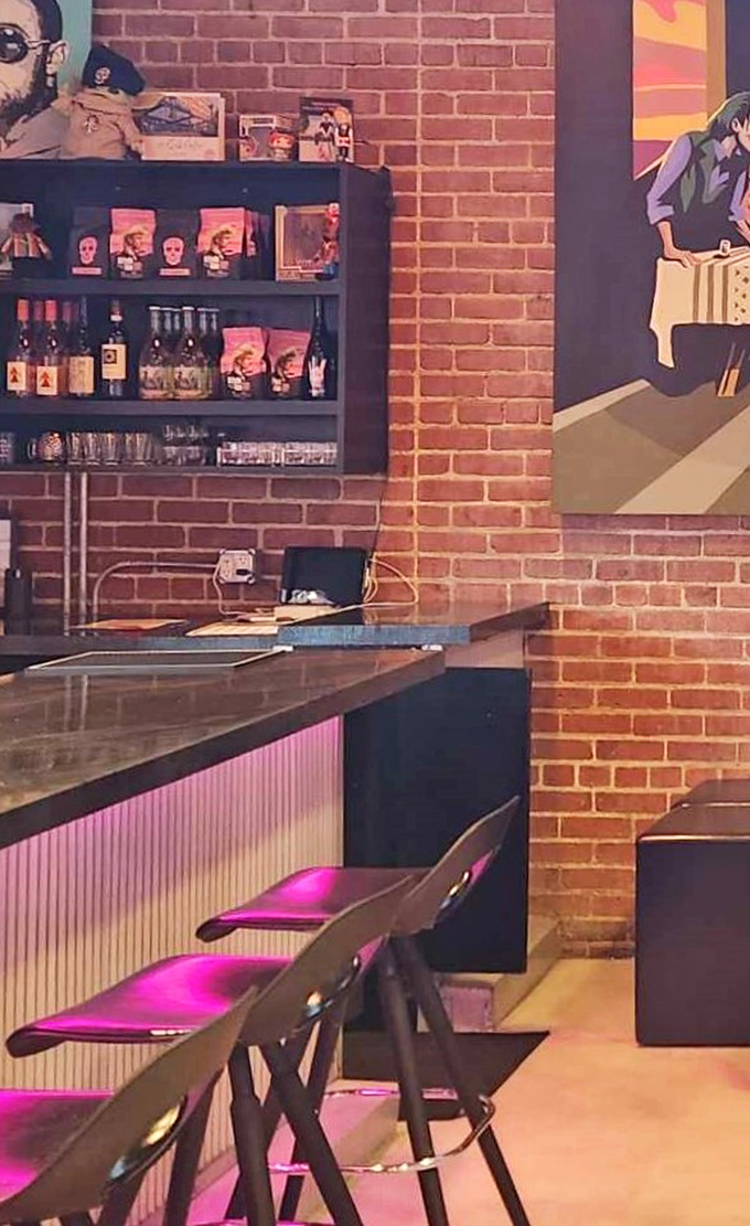 The bar area blends industrial edge with artistic flair—exposed brick, pink lighting, and artwork that reminds you this is no ordinary coffee stop.