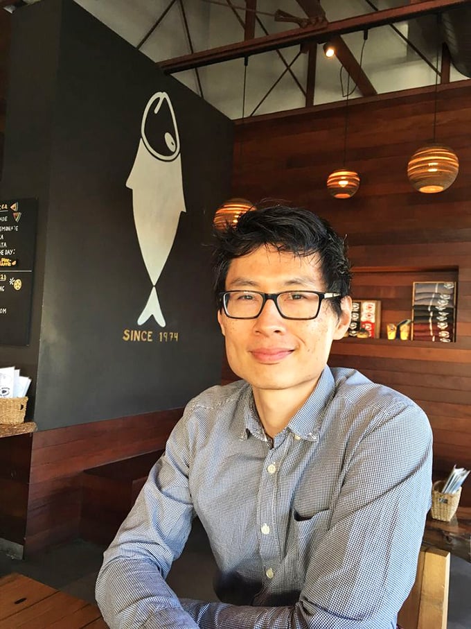 A person enjoying the warm wooden interior with the iconic fish silhouette behind them—this is the face of seafood satisfaction.