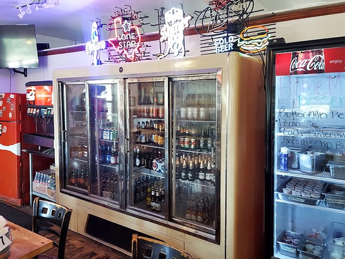 The beer fridge—a shrine to liquid refreshment that perfectly complements those monumental burgers waiting just a few feet away.