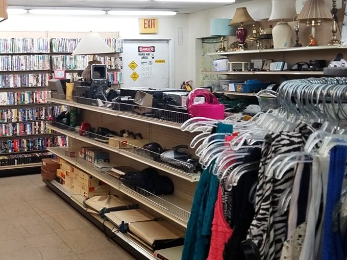 Where media memories and fashion finds collide! DVDs line the shelves while clothing racks stretch toward the horizon – a secondhand symphony of possibilities under fluorescent lights.