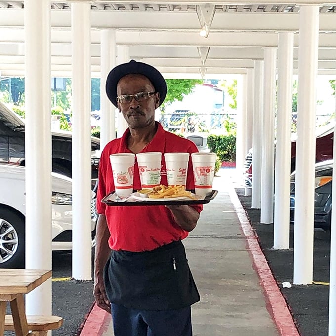 A dedicated server carries the tradition of hospitality on a tray—four drinks and golden fries balanced with the skill that comes from years of practice.