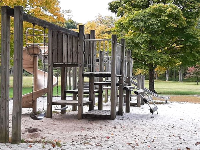 The playground stands ready for tiny adventurers, its wooden structures offering the perfect excuse for parents to say "go burn off some energy!"