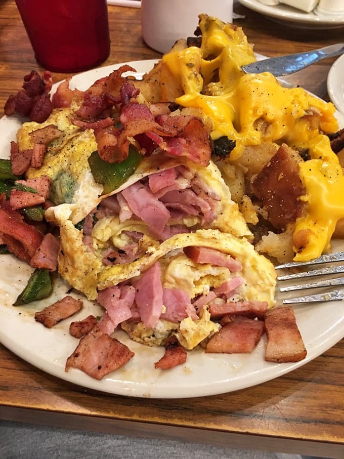 This isn't just an omelet—it's a protein-packed envelope delivering a love letter of ham, bacon, and melted cheese straight to your soul.