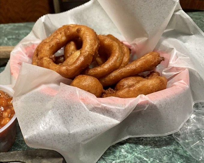 Golden, crispy onion rings nestled in paper—simple pleasures that make you wonder why anyone bothers with fancy appetizers.