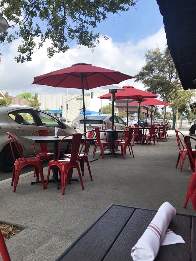 Red umbrella-dotted outdoor seating that says, "Yes, you can enjoy your ribs in California sunshine without a hint of irony."