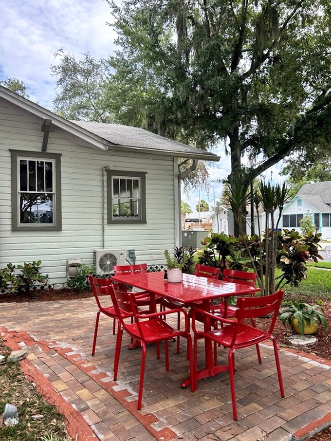 Those red chairs aren't just furniture—they're an invitation to linger under Florida's oak trees with a coffee and watch the world go by.