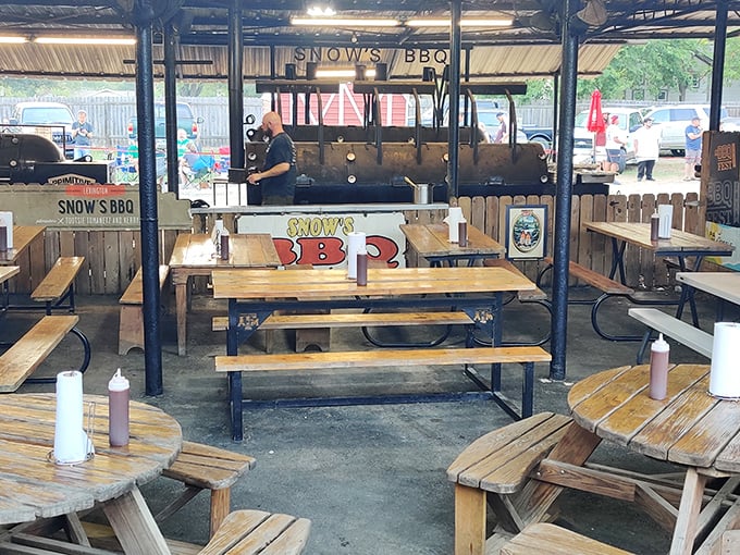 The outdoor pit area – barbecue's sacred temple where smoke rises like prayers and picnic tables await the faithful with rustic simplicity.