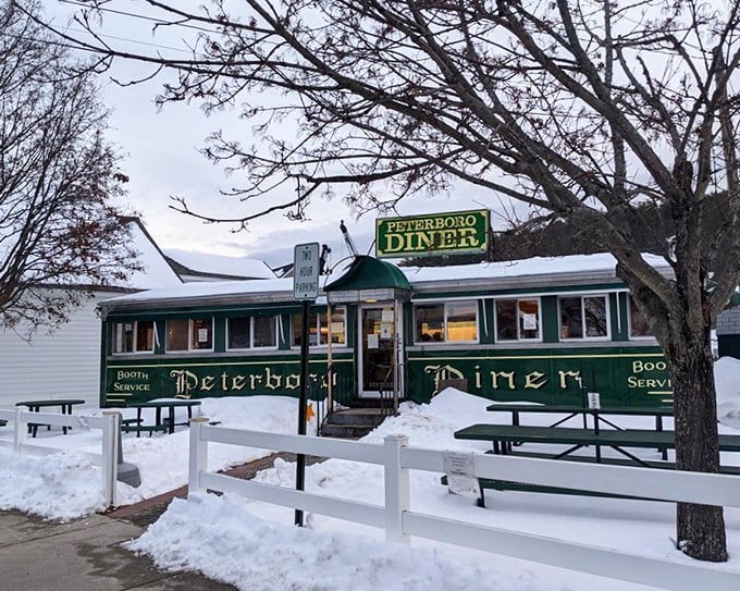 Even in winter's embrace, the Peterborough Diner stands defiant—a warm green beacon promising comfort food salvation amid New Hampshire snowdrifts.