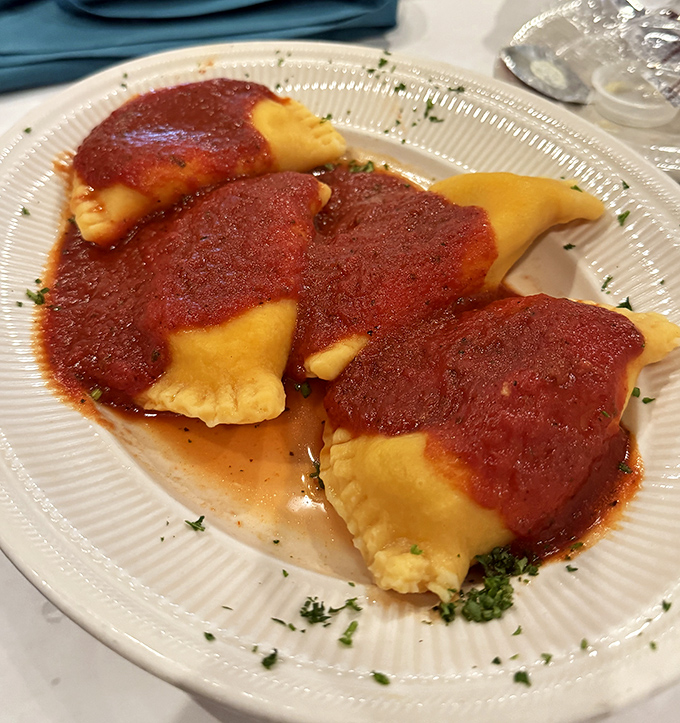 These ravioli swimming in rich tomato sauce aren't just pasta – they're edible time machines transporting you to Sunday dinners at Nonna's house.