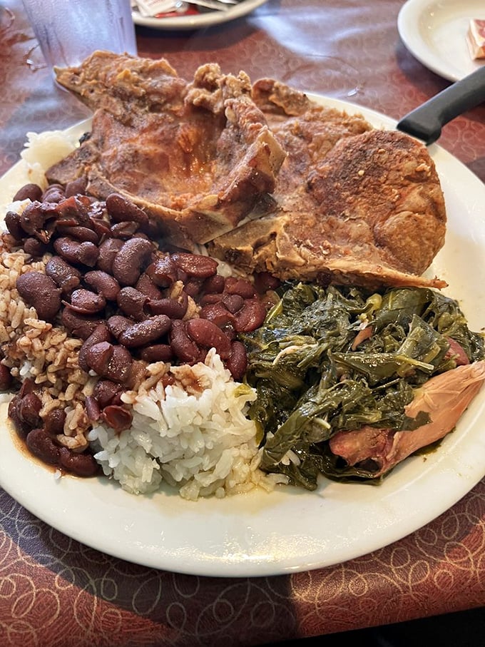 Soul food royalty on a plate—pork chop, collard greens, and red beans over rice that taste like they've been simmering since yesterday.